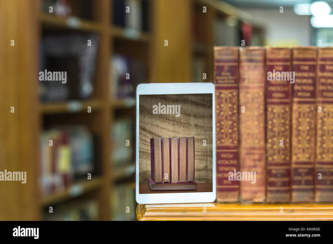 Tablet computer with old books on the wood table in library, Education ...