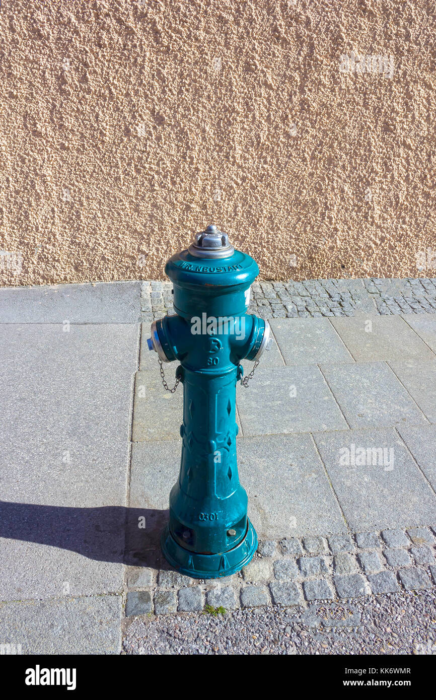 The green old fireplug against a stone wall background Stock Photo - Alamy