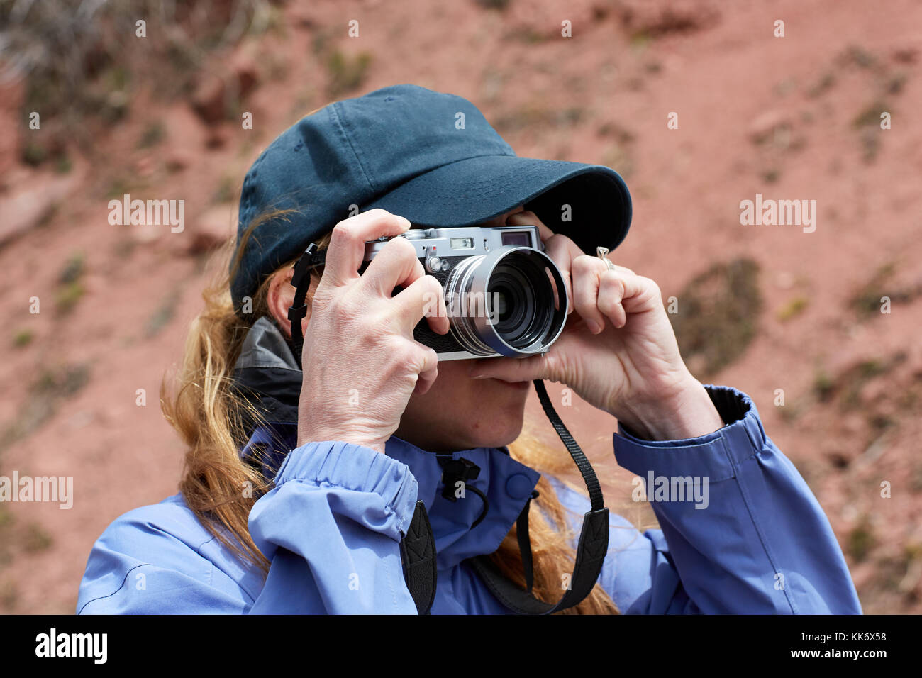 Woman in a baseball cap taking a photograph holding the camera to her ...