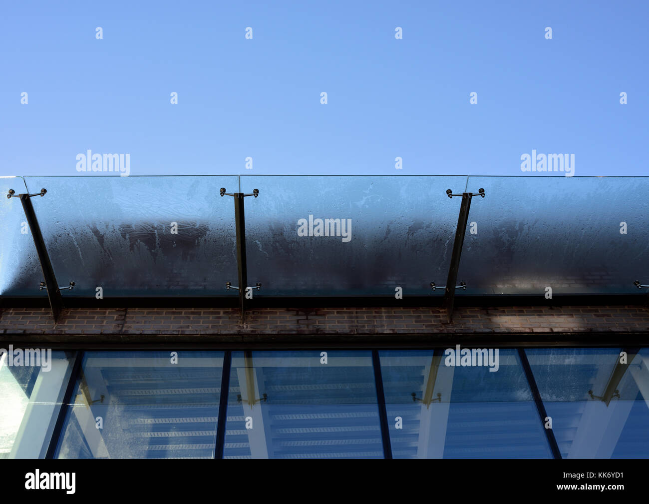 Glass canopy suspended on stainless steel brackets above glass curtain ...