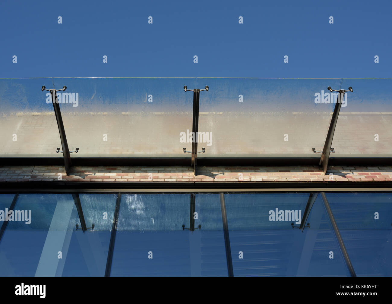 Glass canopy suspended on stainless steel brackets above glass curtain ...