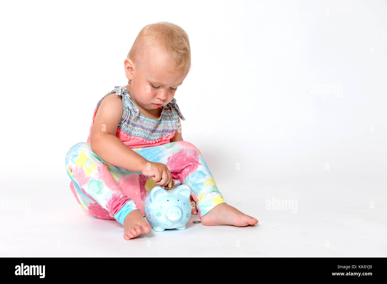 Cool toddler girl sitting on the floor is throwing coin into saving ...