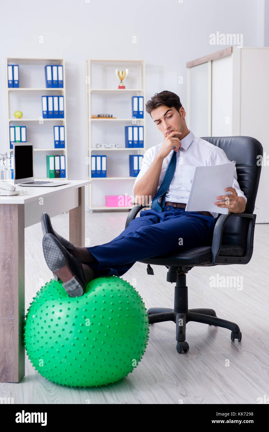 Young businessman doing sports stretching at workplace Stock Photo - Alamy