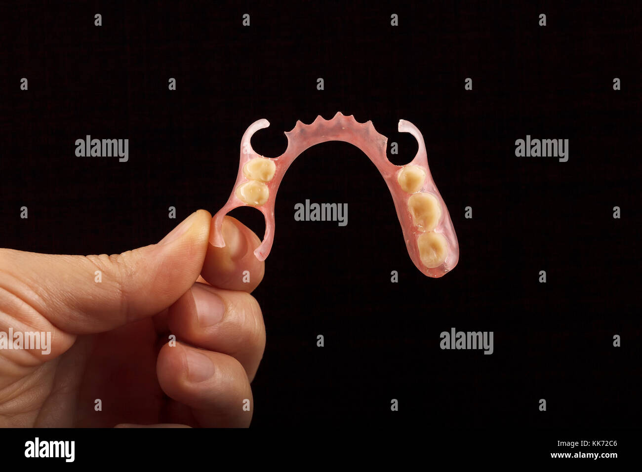 Dental prosthesis in the hand of the dentist. Close-up on a black ...
