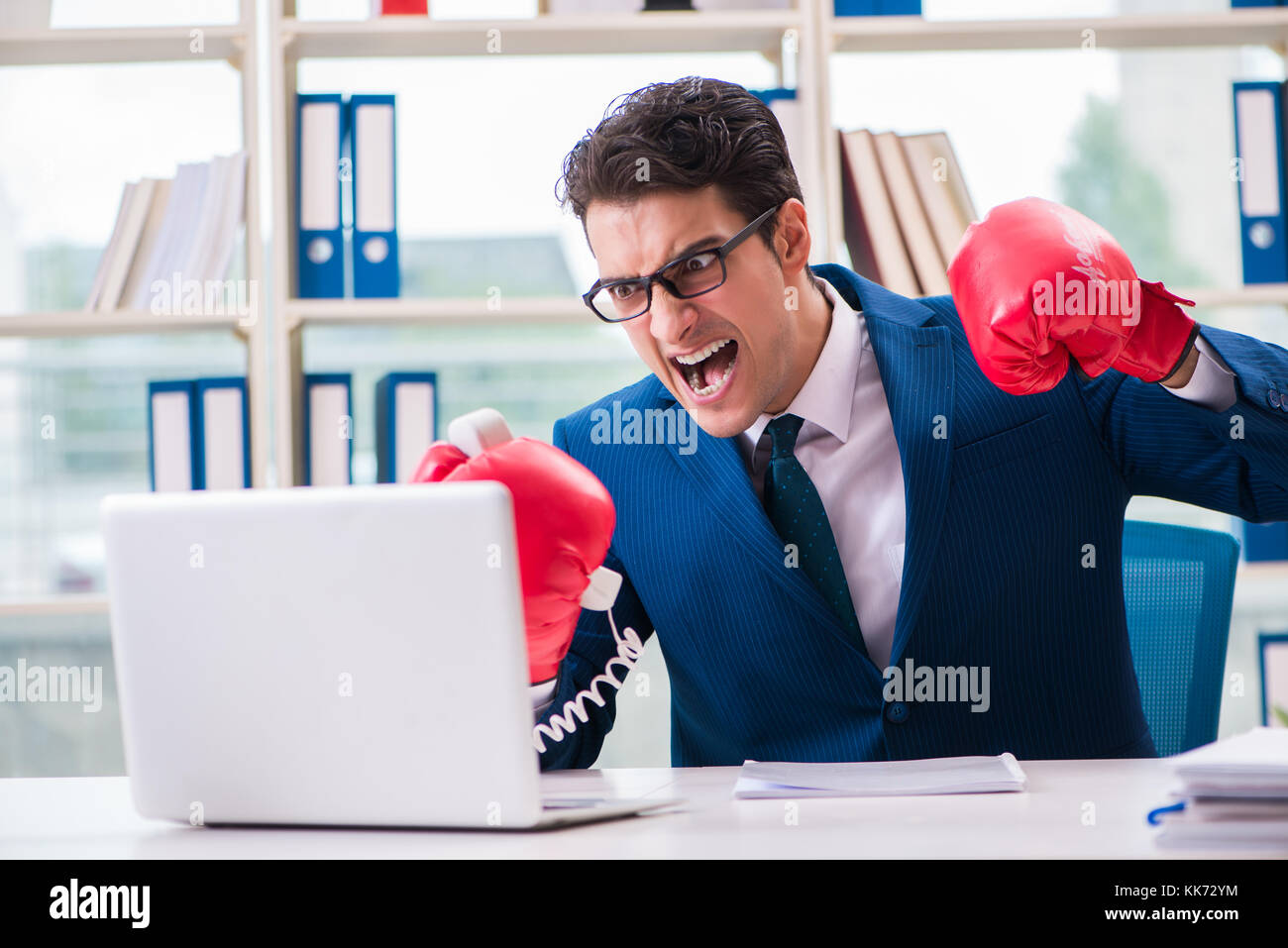 Businessman with boxing gloves angry in office Stock Photo - Alamy