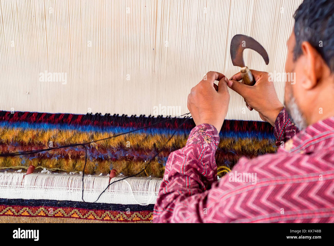 Back view man weaves carpet Stock Photo - Alamy