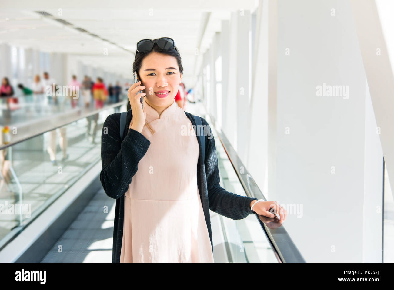 Girl using phone while on the moving walkway inside Stock Photo - Alamy