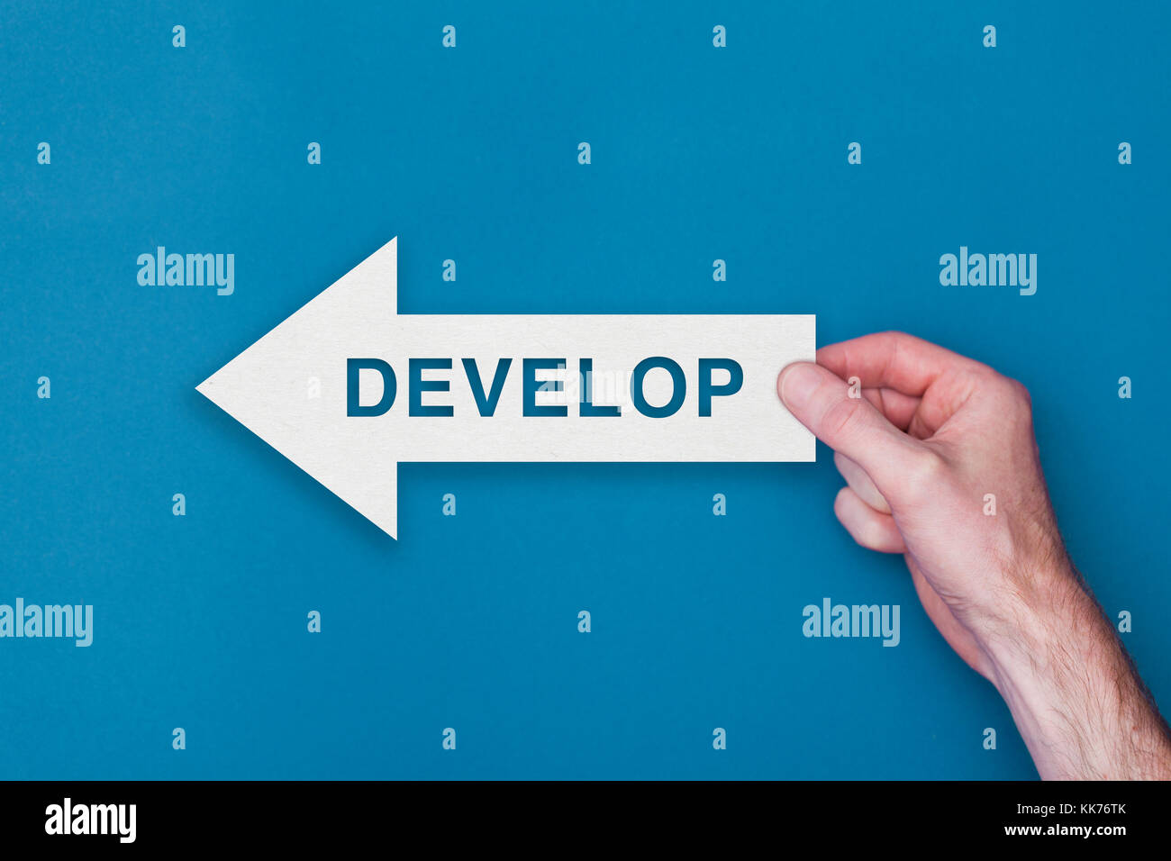 Develop arrow direction held on a blue background Stock Photo - Alamy