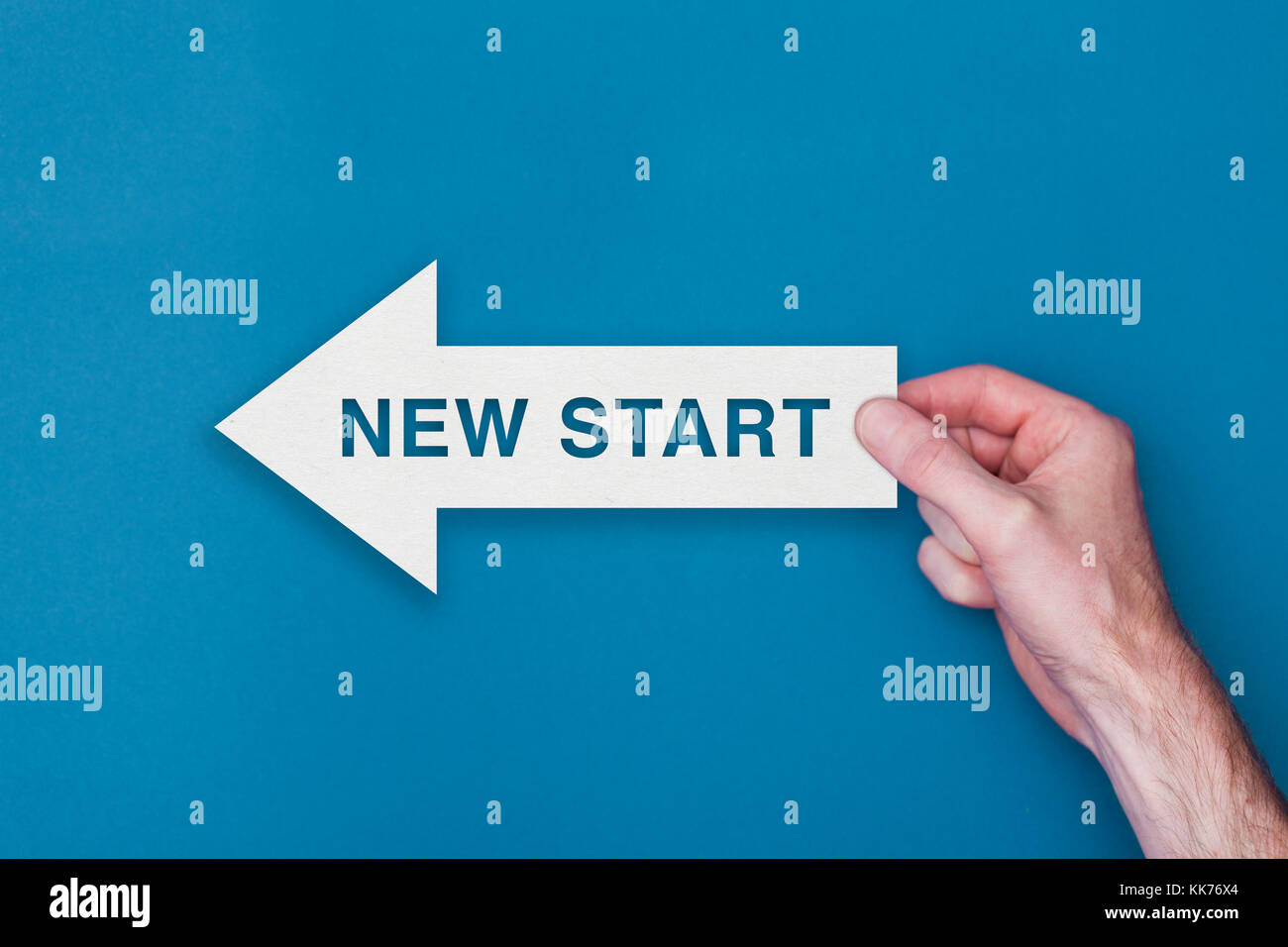 New Start arrow direction held on a blue background Stock Photo - Alamy
