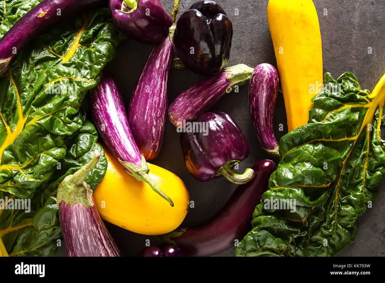 Small eggplant, yellow zucchini, chard and purple pepper. Dark ...