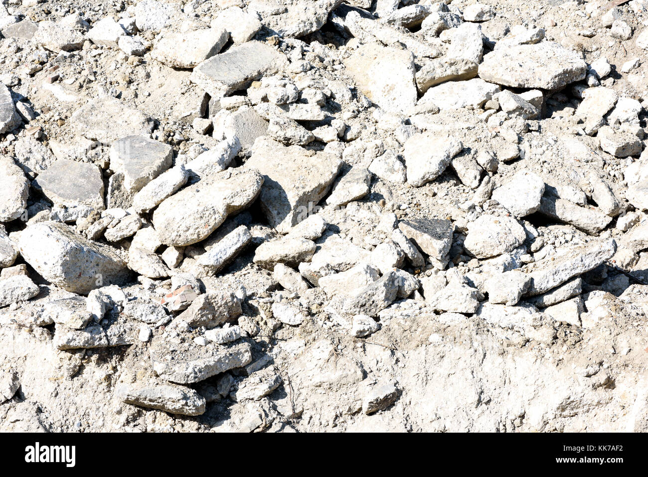 White piles of hardcore rock rubble from broken cement on the ground ...