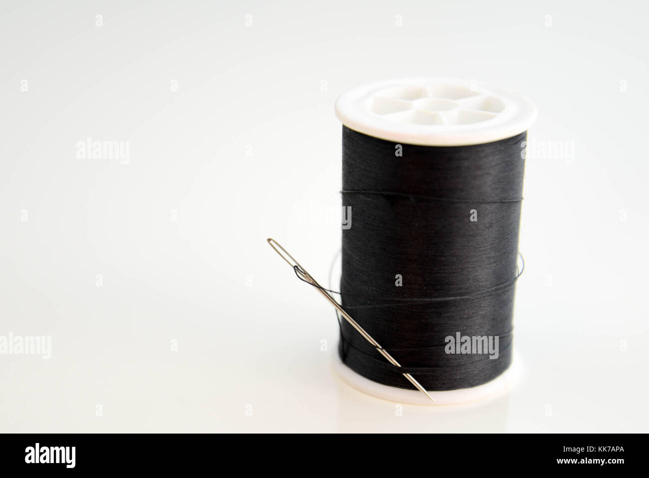 black spool of thread and needle stuck in the thread Stock Photo - Alamy