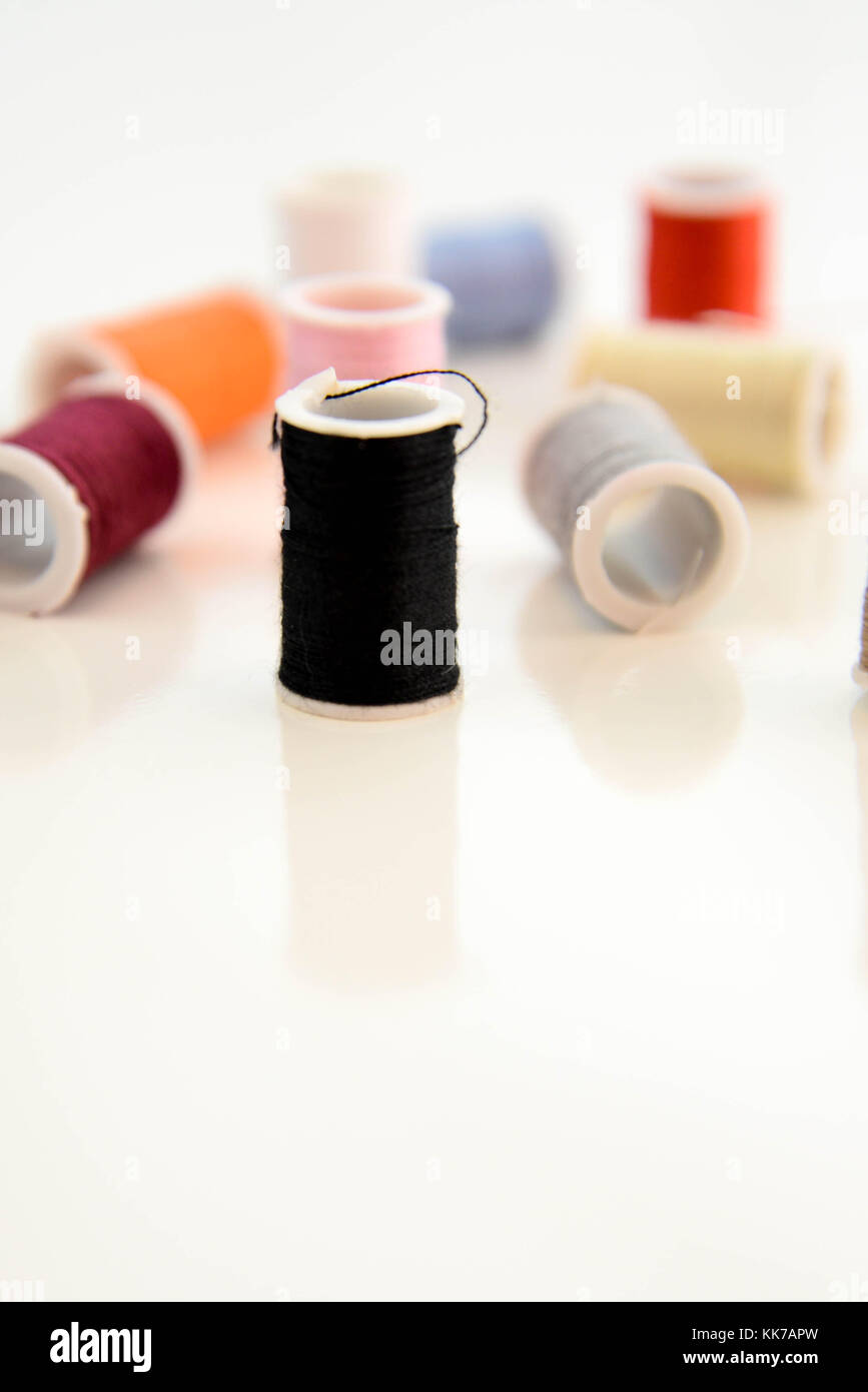 red thread through needle eye and red button with multi colored thread ...