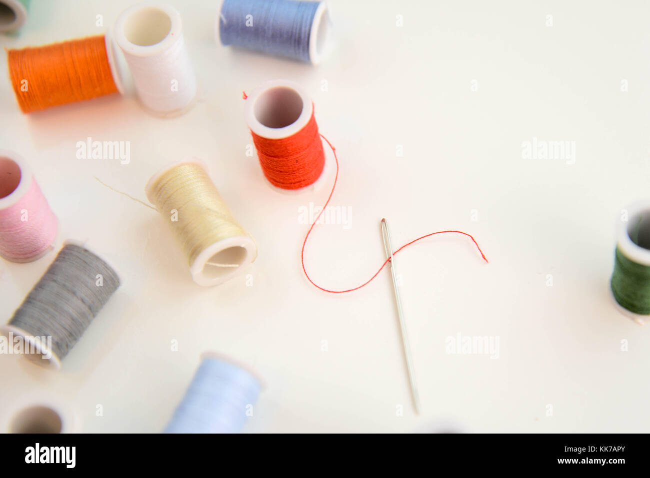 threaded needle, red thread spool, and multi colored spools. red, green ...