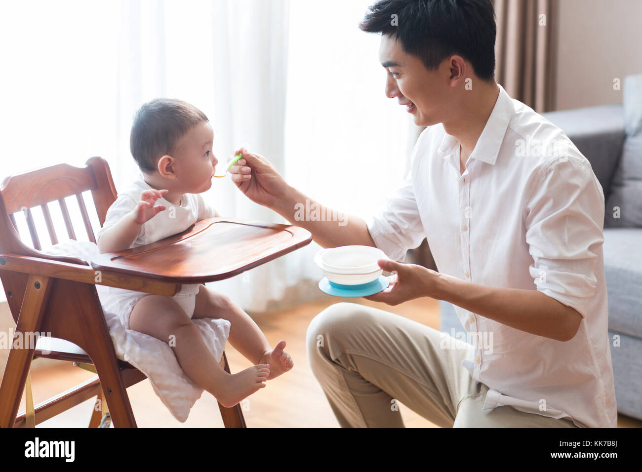 Young Chinese father feeding baby Stock Photo - Alamy