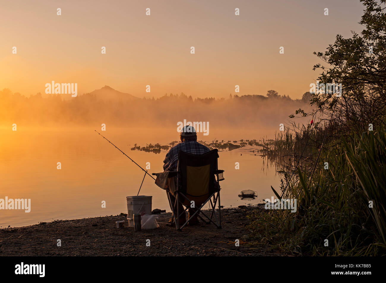 Fisherman on Lake Cassidy casting line at sunrise with Mount Pilchuck ...