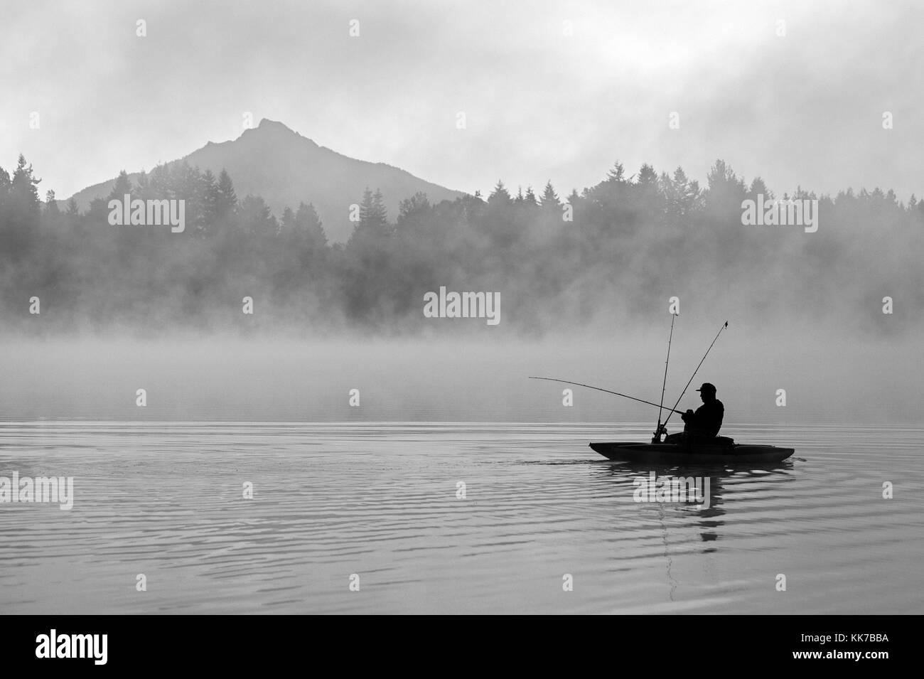 Fisherman on Lake Cassidy casting line at sunrise with Mount Pilchuck ...