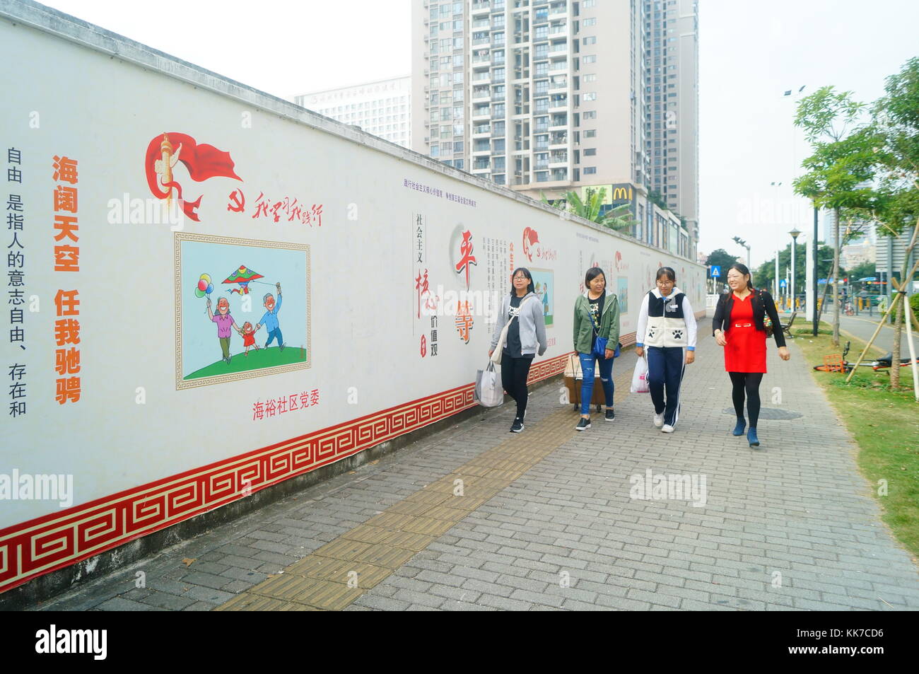 Shenzhen, China: street propaganda walls, painted walls, tourists pass ...