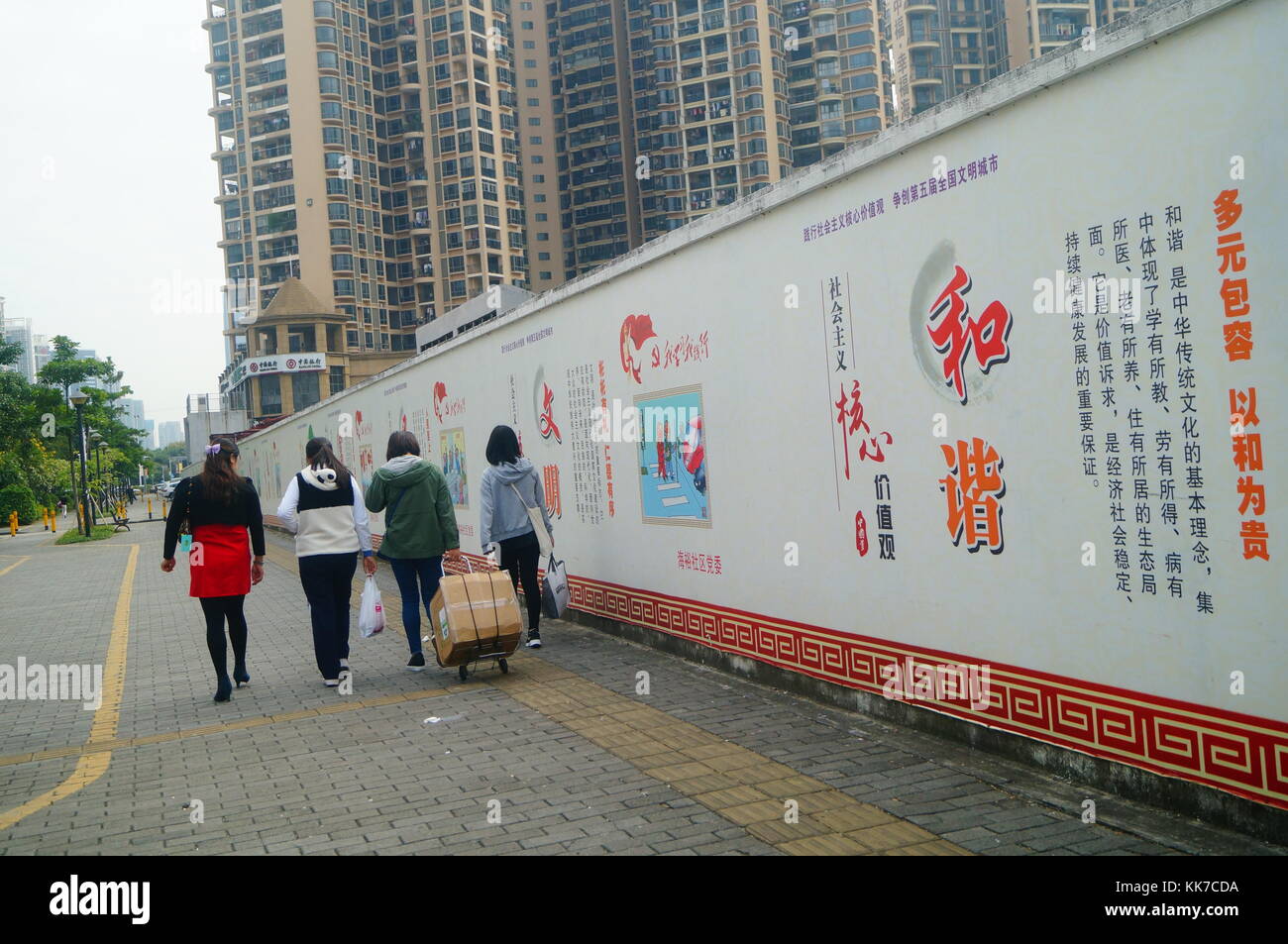 Shenzhen, China: street propaganda walls, painted walls, tourists pass ...