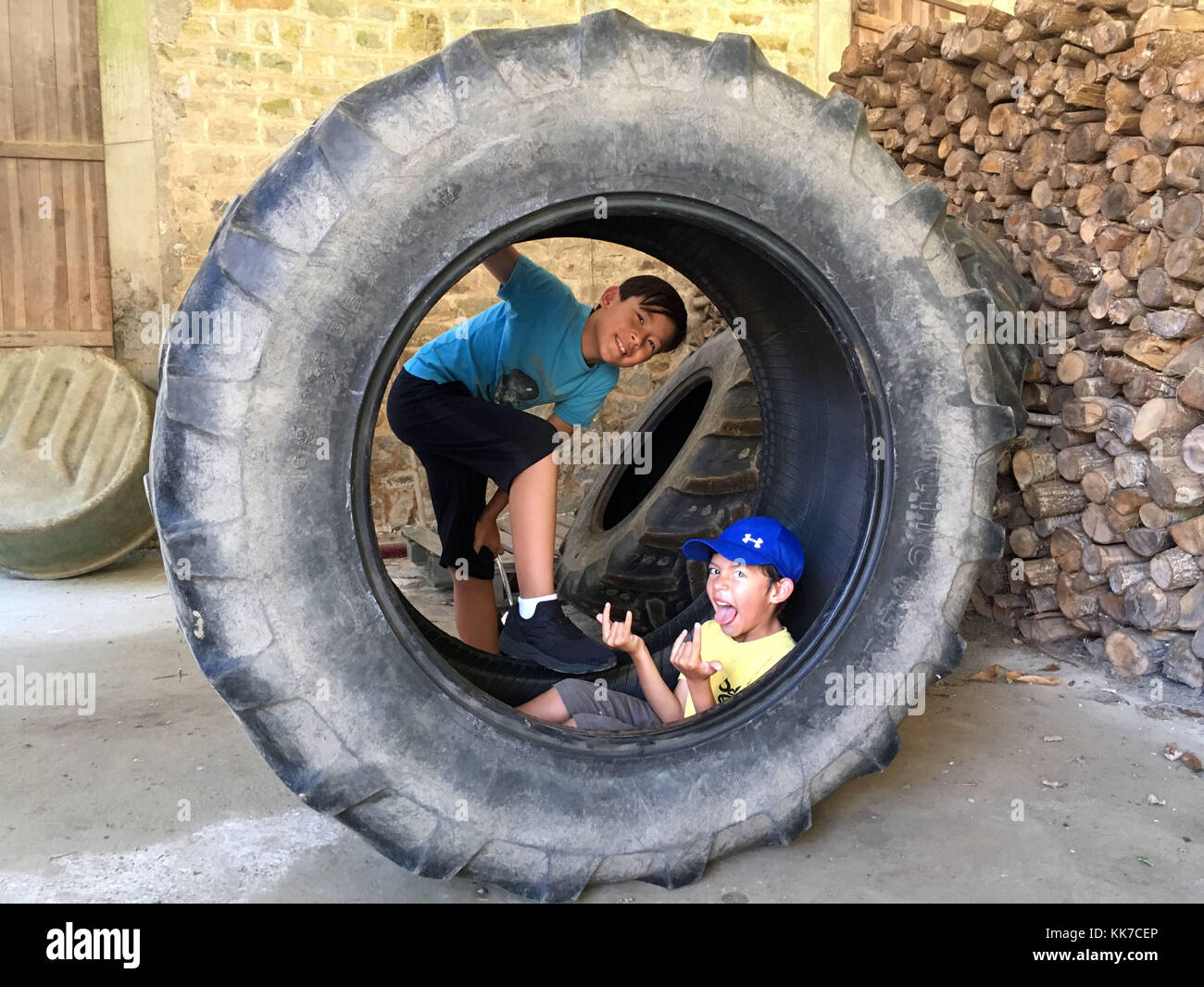2 young boy brothers or friends playing in a farm in a giant tractor ...