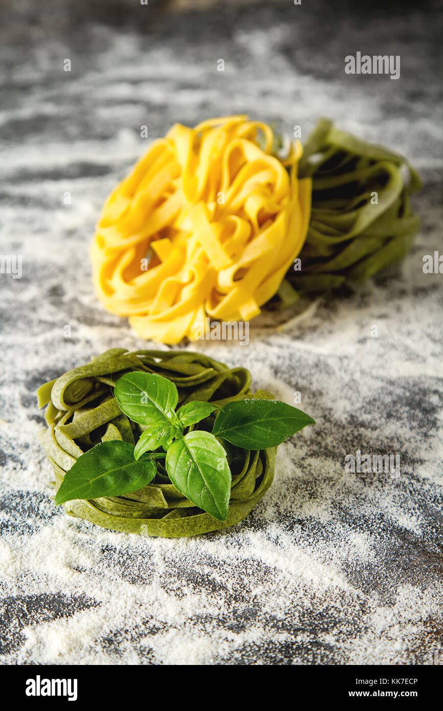 Homemade italian tagliatelle with flour and basil. Dark background ...