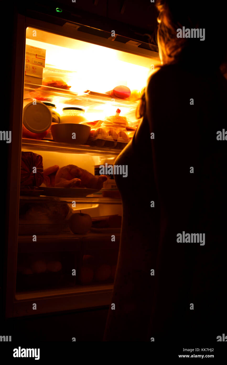 Woman looking into refrigerator in the middle of night looking for ...