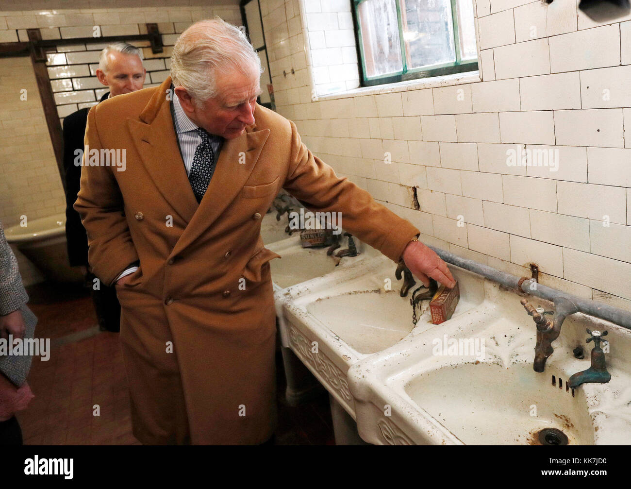 The Prince of Wales looks at a sink inside the original workers' bath ...