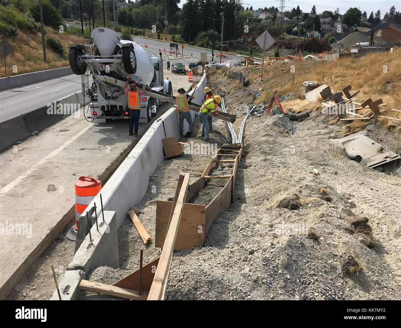 Construction crews install conduits and backfill the trench on the back ...