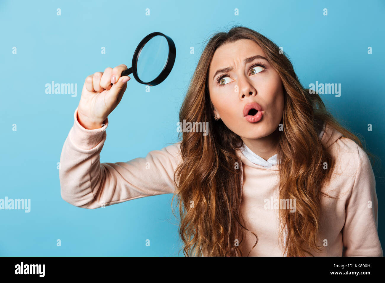 Close up portrait of a funny positive girl looking through magnifying ...