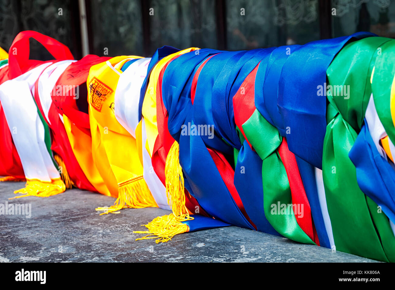 Red, green, gold and white taoist prayer ribbons hanging from a stand ...