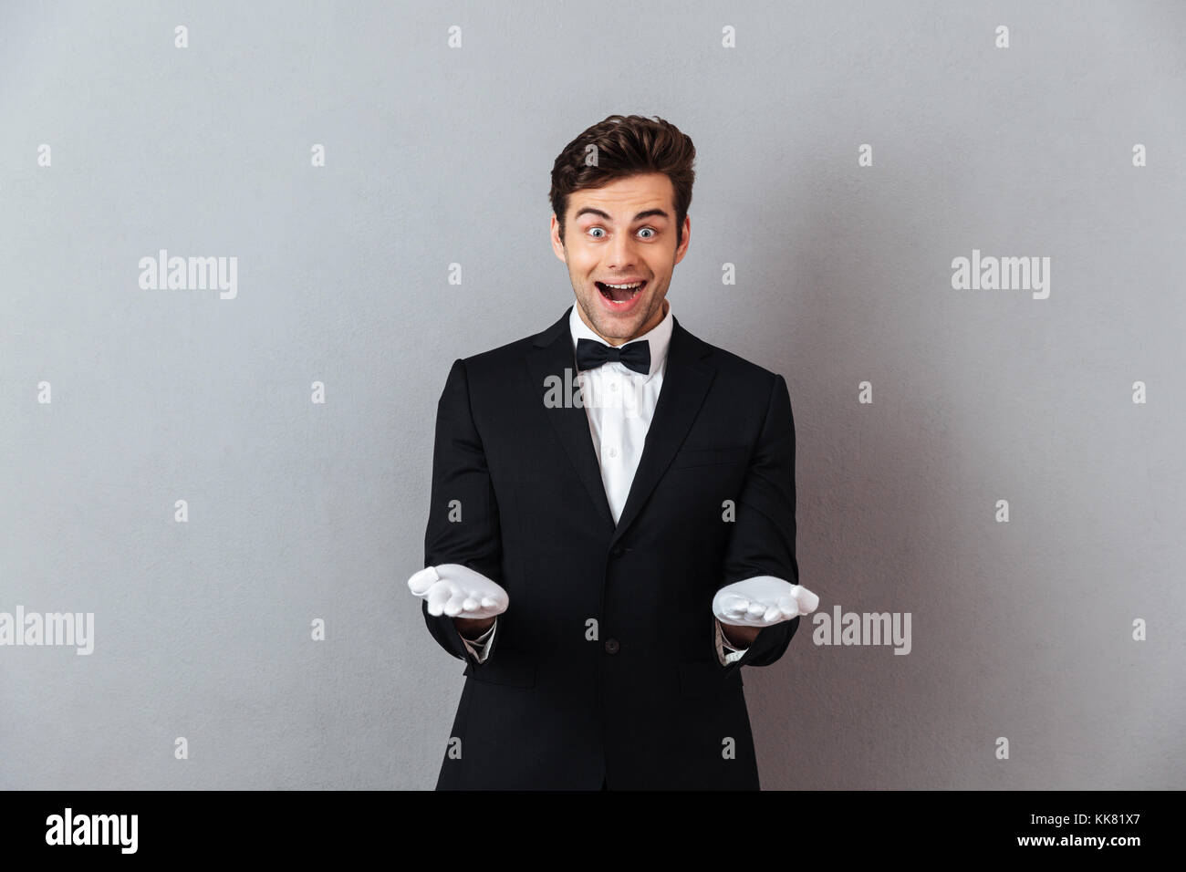 Image of surprised young waiter standing isolated over grey wall ...