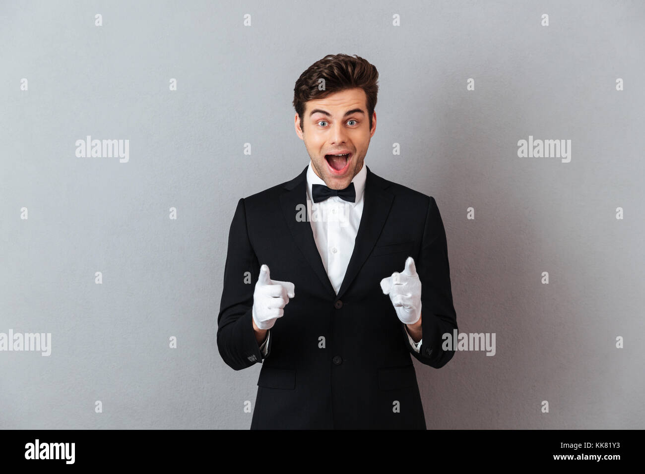 Image of surprised happy young waiter standing isolated over grey wall ...