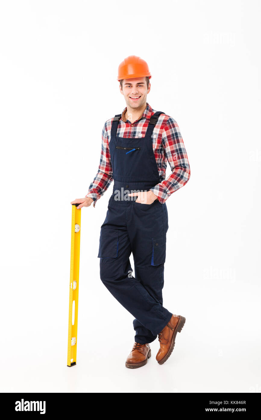 Full length portrait of a smiling young male builder holding spirit ...