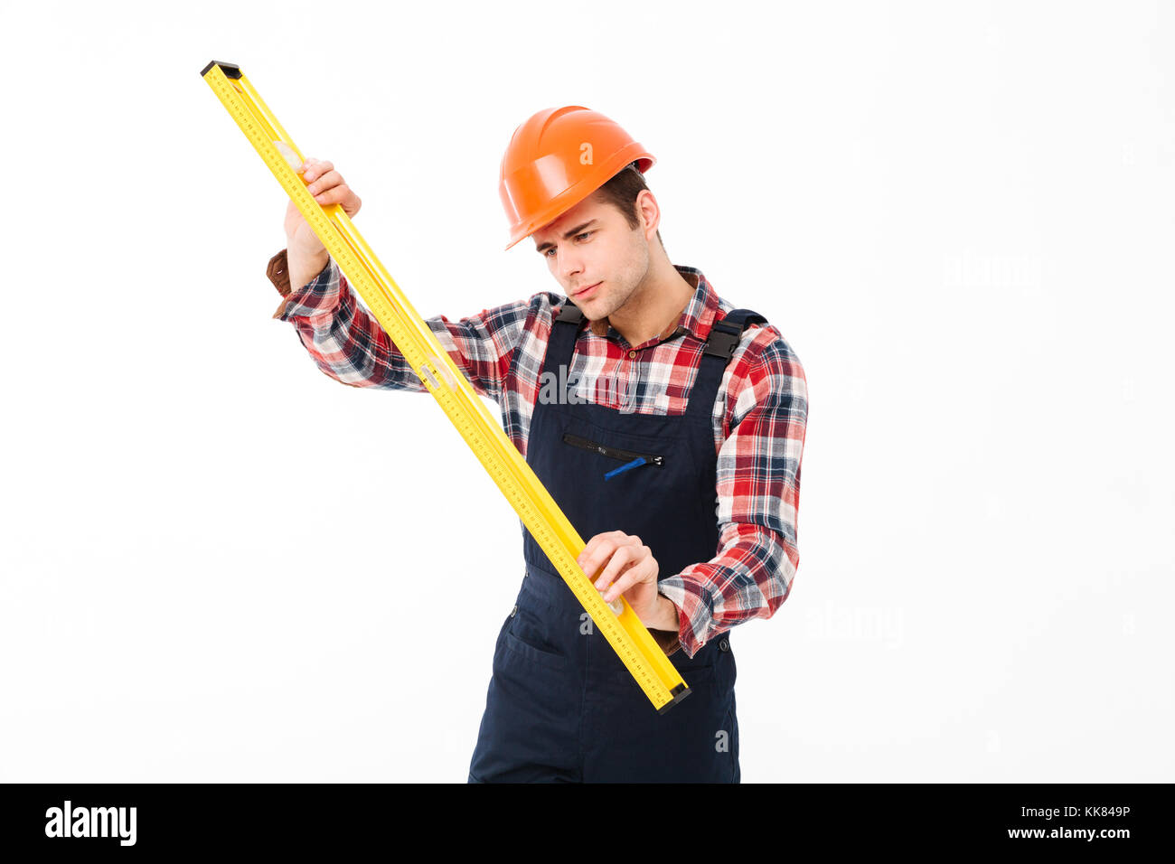 Full length portrait of a concentrated young male builder using spirit ...