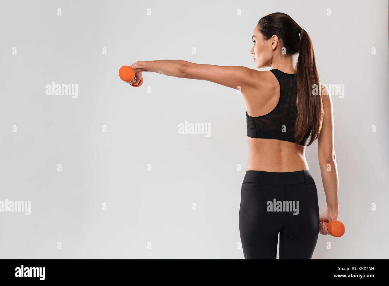 Back view image of concentrated young sports woman make exercises with ...