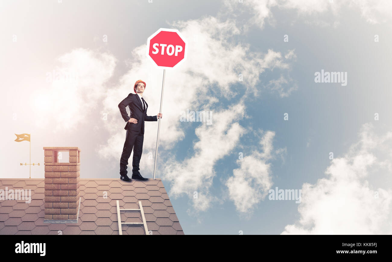 Caucasian businessman on brick house roof showing stop road sign Stock ...