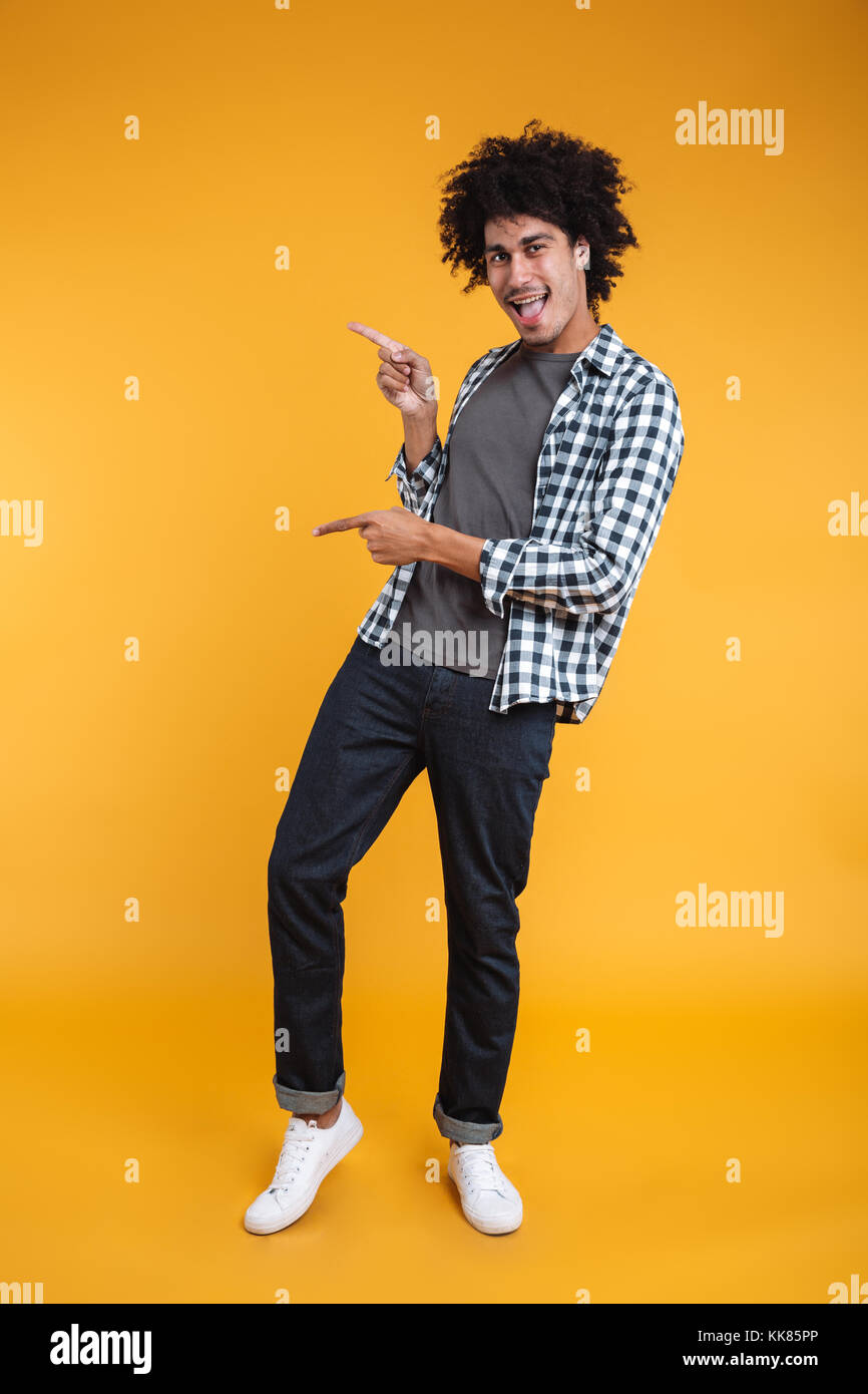 Full length portrait of a cheerful young african man pointing fingers ...