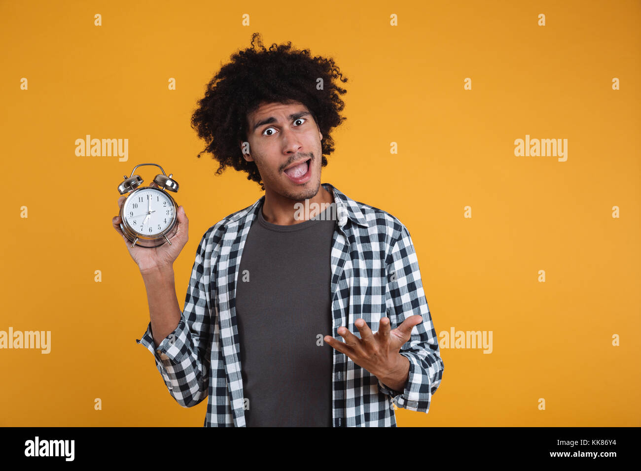 Portrait of an excited surprised african man holding alarm clock ...