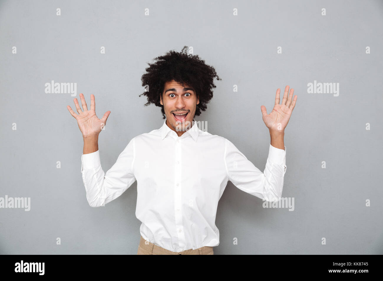 Portrait of a cheery young african man holding hands raised and ...