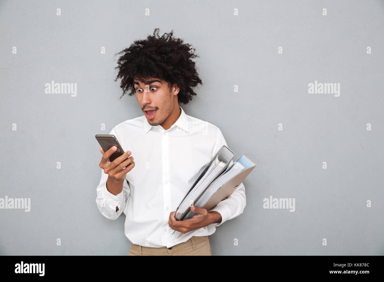 Portrait of a scared young afro american man looking at mobile phone ...