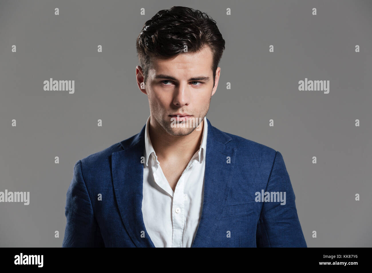 Portrait of a charming young man in jacket posing while standing ...