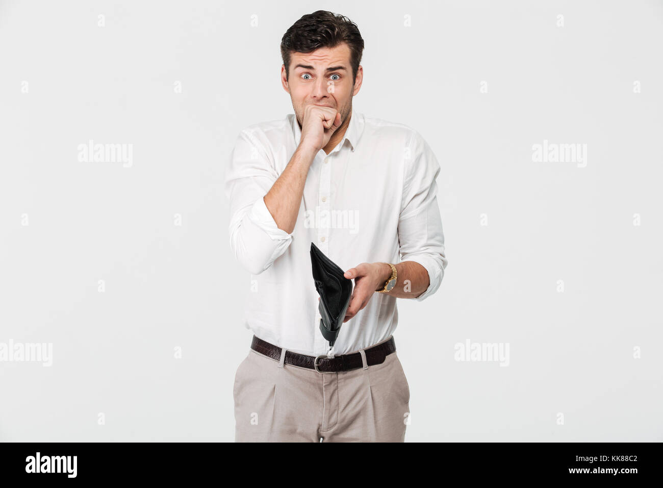 Portrait of a scared worried man showing empty wallet and looking at ...