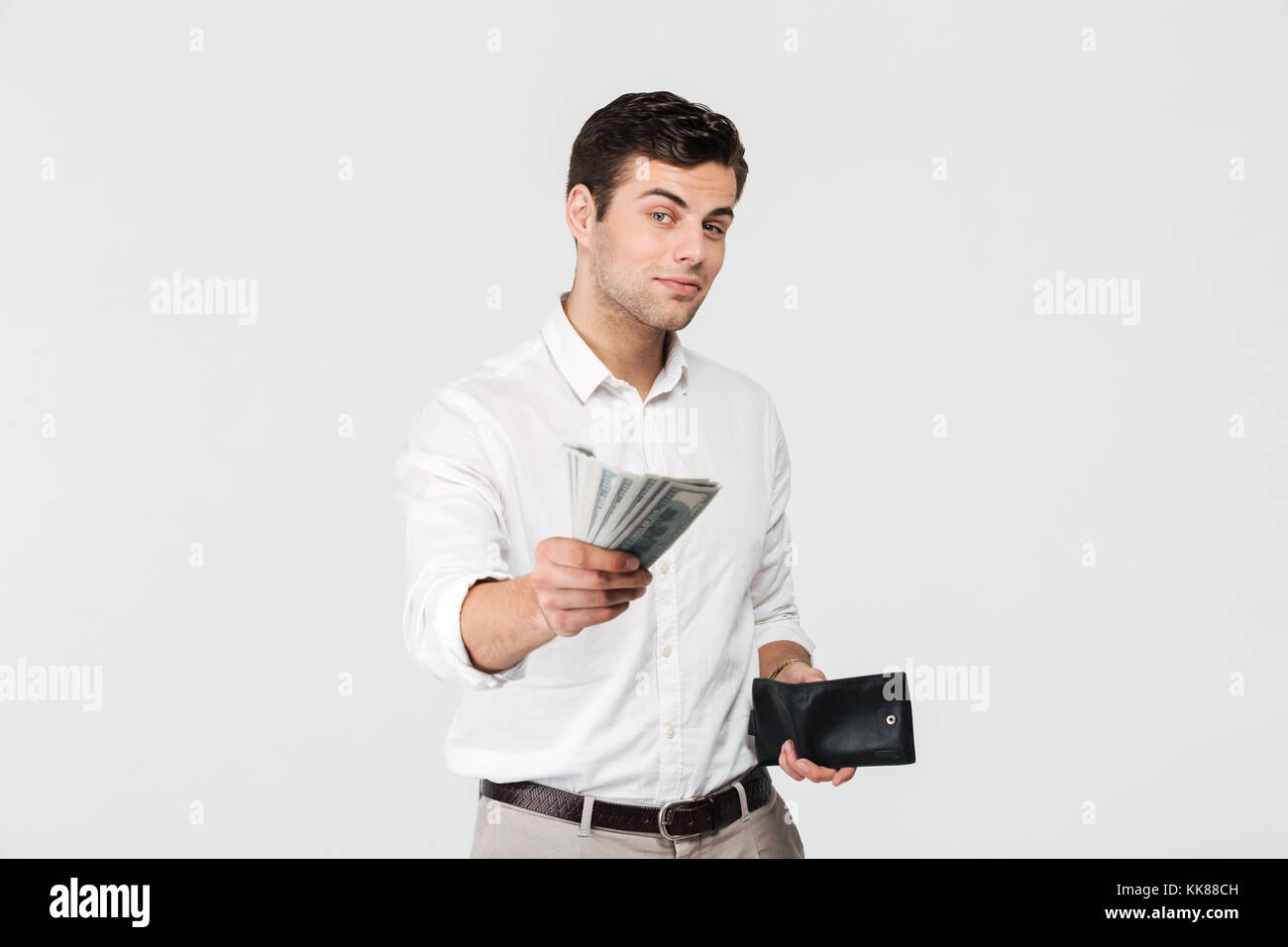 Portrait of a successful smiling man holding wallet and giving money ...