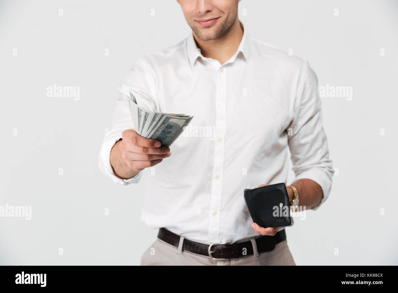 Cropped image of a smiling man holding wallet and giving money ...