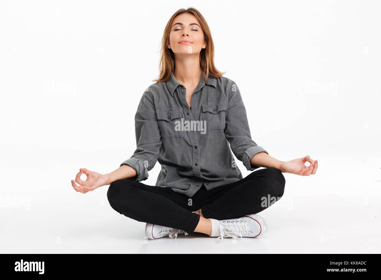 Portrait of a smiling calm girl meditating in lotus position with eyes ...