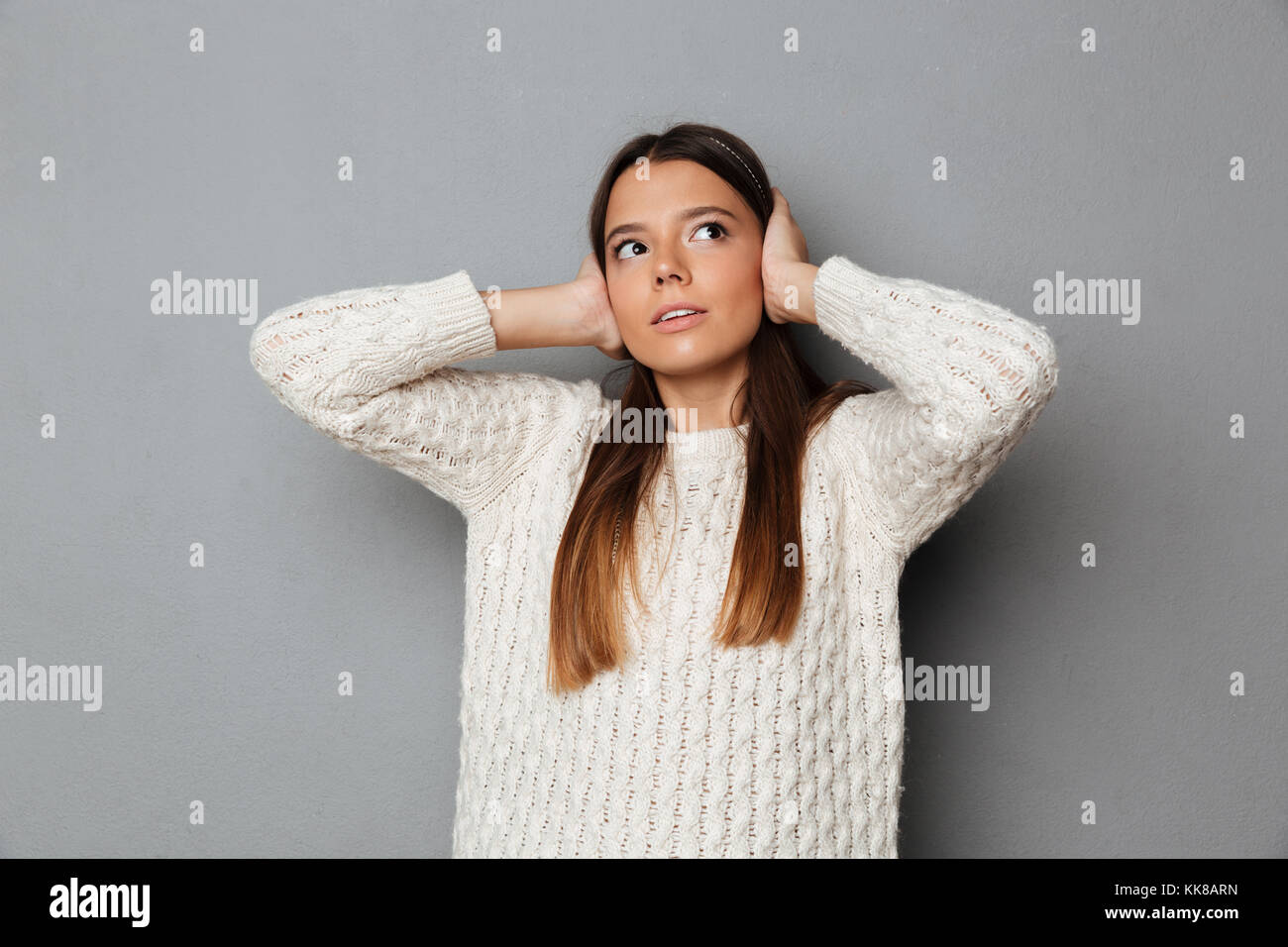 Portrait of a young worried girl in sweater closing hands with hands ...