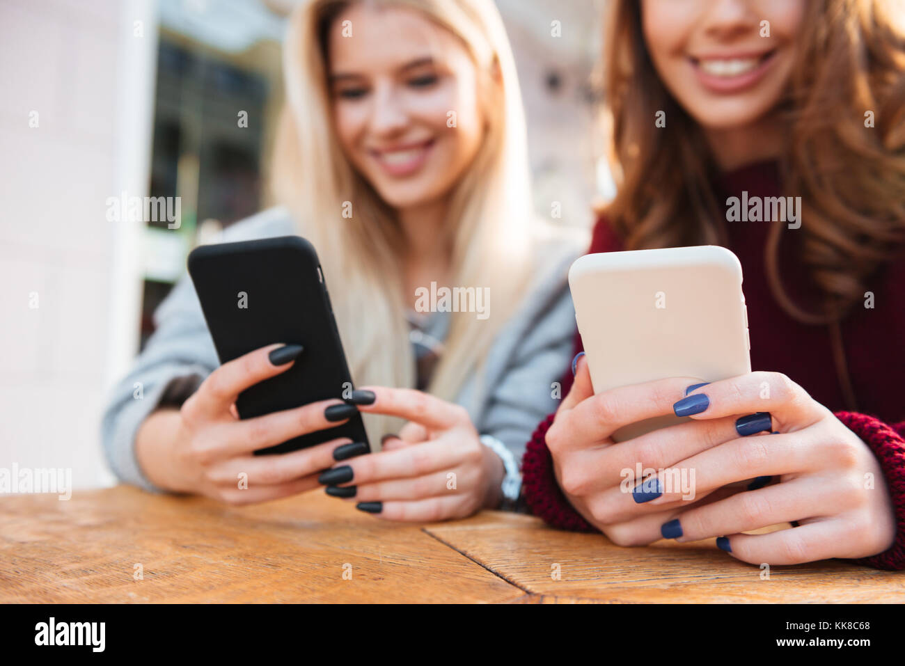 Close Up Portrait Of Two Smiling Girls Holding Mobile Phones While