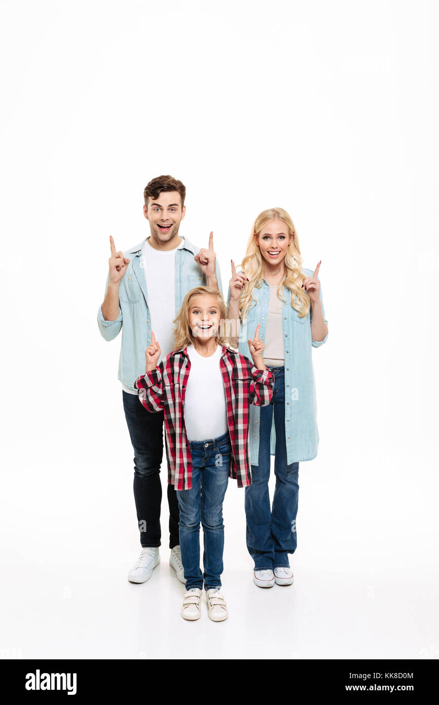 Full length portrait of a joyful young family with a child standing ...