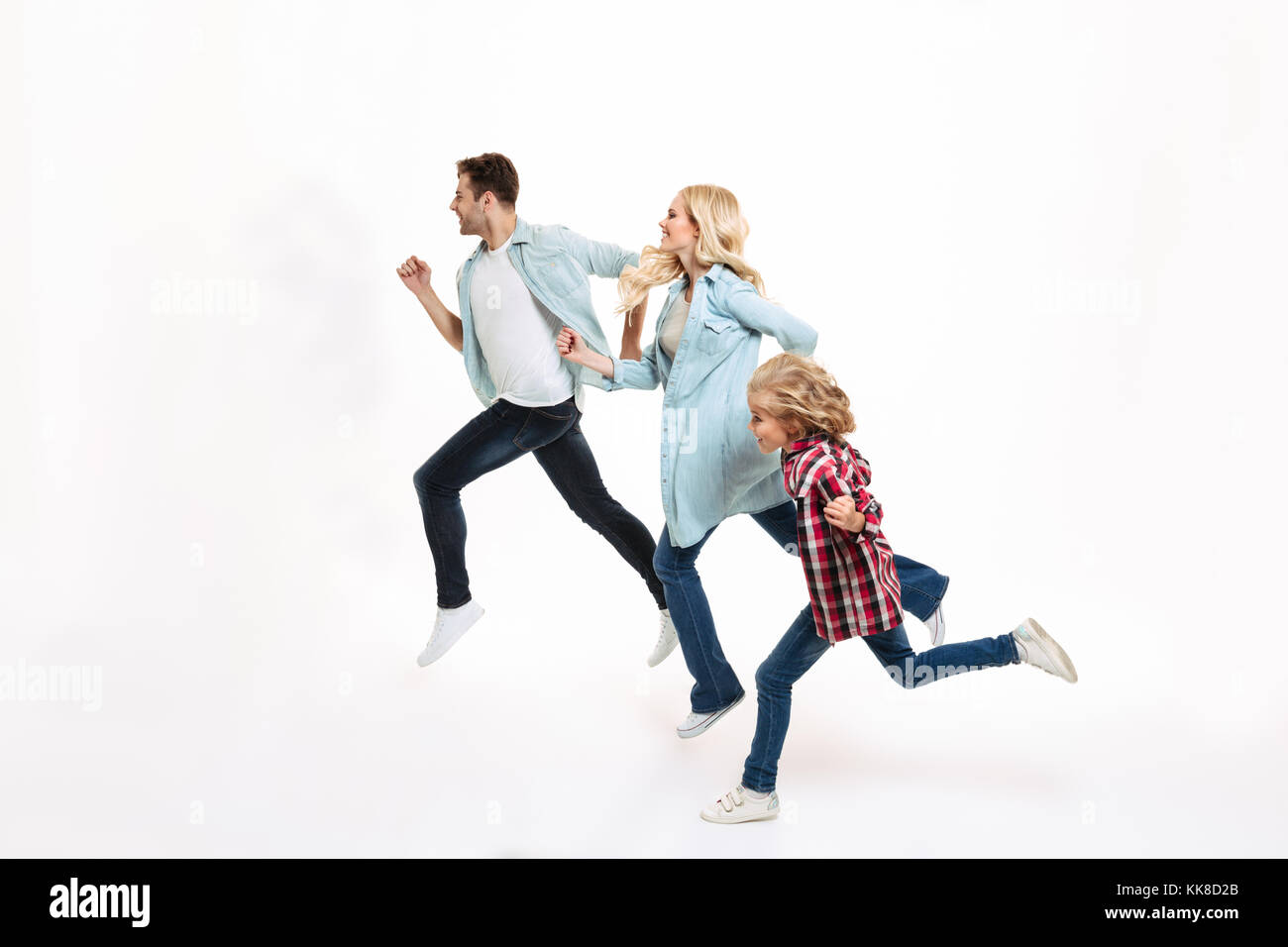 Full length portrait of a young modern family with a child running ...