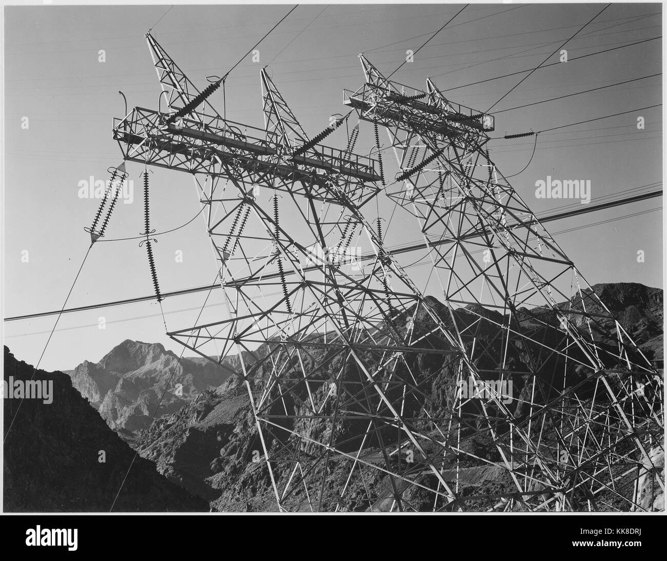A black and white photograph of transmission line towers on a cliff ...